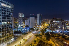 Paisagem urbana noturna com edifícios modernos, ruas largas e áreas iluminadas.