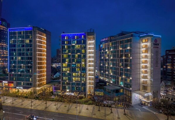 Um hotel moderno com vários andares, grandes janelas e letreiros iluminados.