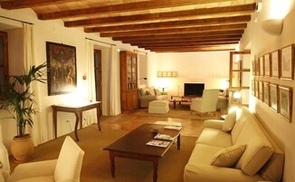 Uma sala de estar acolhedora com teto de madeira, um conjunto de sofá, uma mesa de centro e uma televisão.