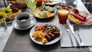 Uma mesa de café da manhã com diversos pratos, incluindo ovos, salsichas e torradas.