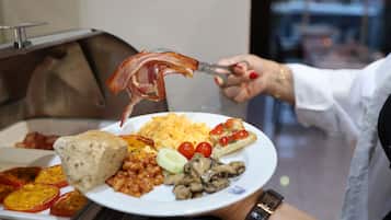 Prato de comida de café da manhã com ovos, bacon, tomates, cogumelos, feijão e torradas.