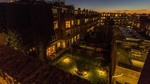 Um edifício residencial alto com várias varandas e um pátio com piscinas iluminadas.