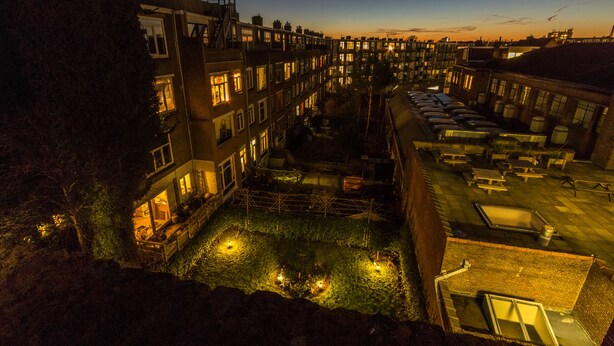 Um pátio com piscina, rodeado por edifícios escalonados com várias janelas e varandas.