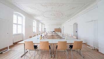 Uma sala de conferências com uma longa mesa, cadeiras e teto branco com detalhes artísticos.