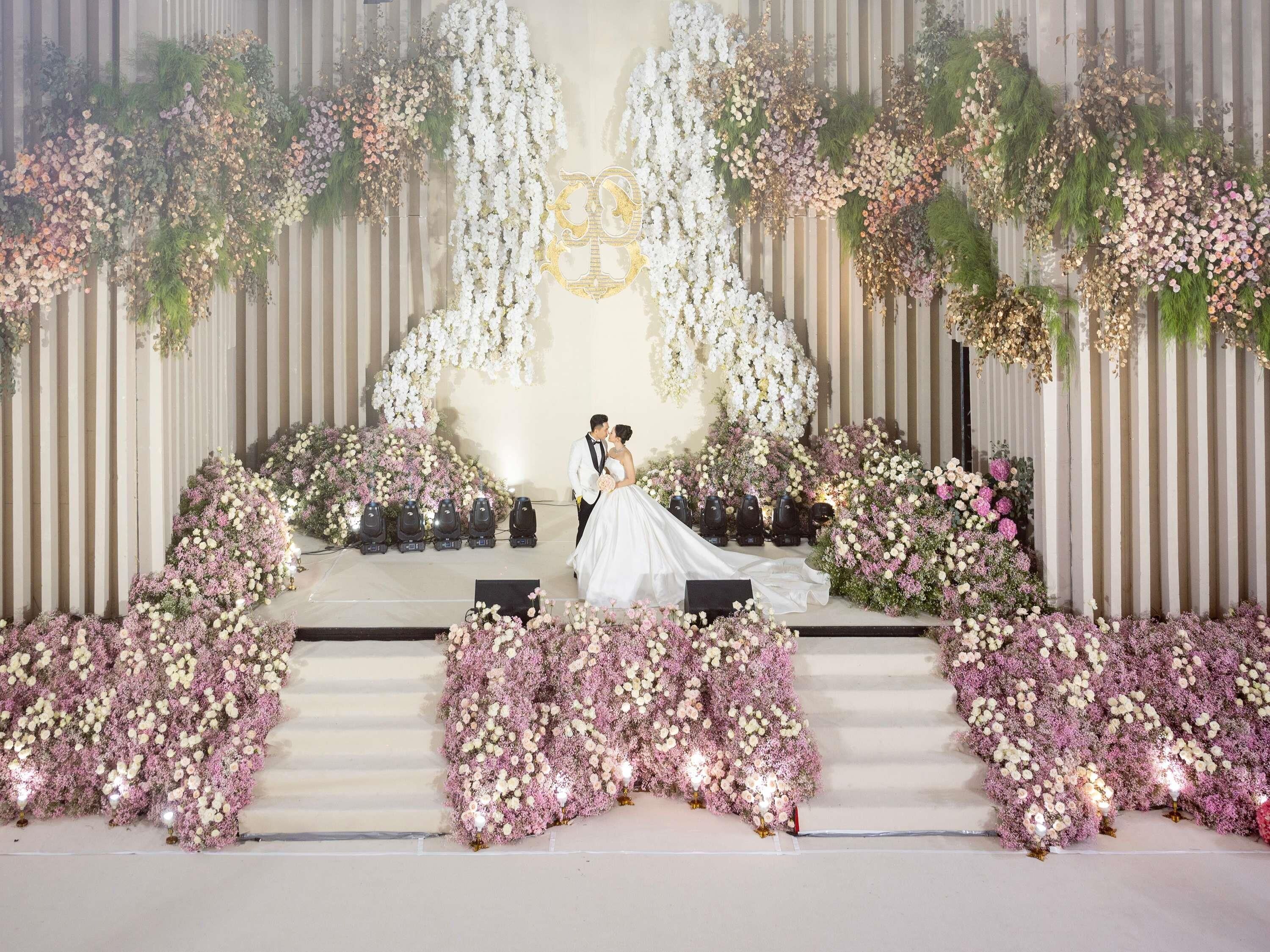 Palco de casamento com arranjos florais e um casal.