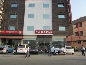 Um hotel chamado HOTEL VENUS, com fachada moderna, várias janelas e uma placa chamativa.