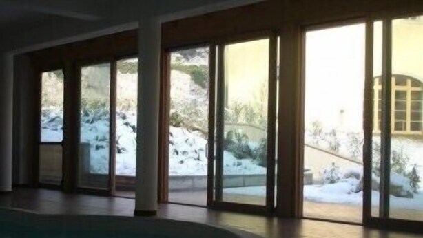 Piscina com grandes portas de vidro que dão para uma área externa coberta de neve.