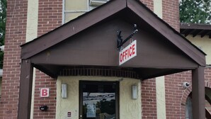 Um edifício com telhado marrom, uma placa com a inscrição