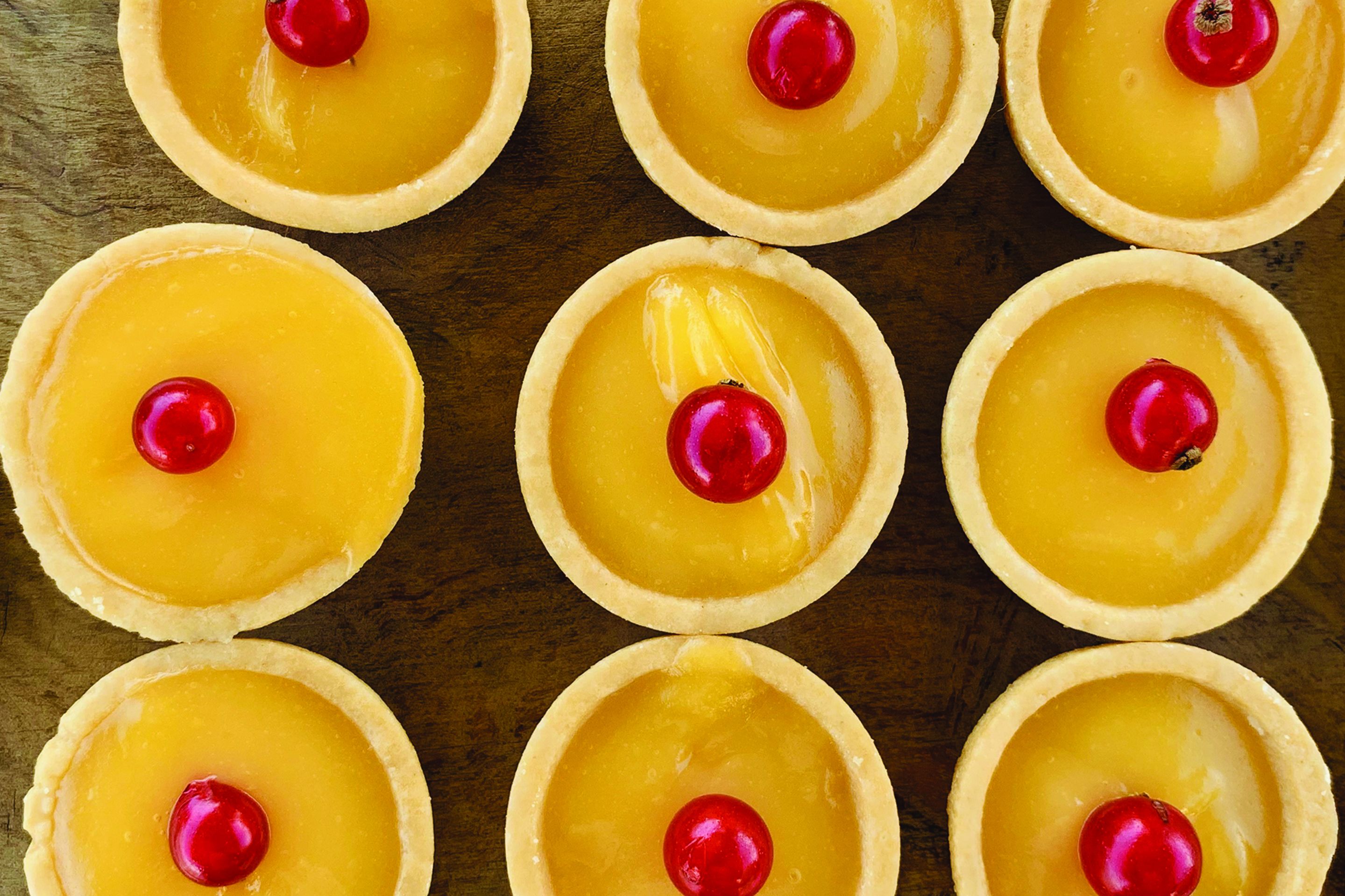 Uma dúzia de pequenas quiches dispostas em grade sobre uma superfície de madeira.