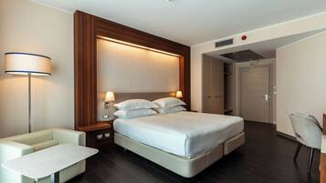 Quarto de hotel moderno com uma cama grande, mesas de cabeceira, uma escrivaninha e uma cadeira.