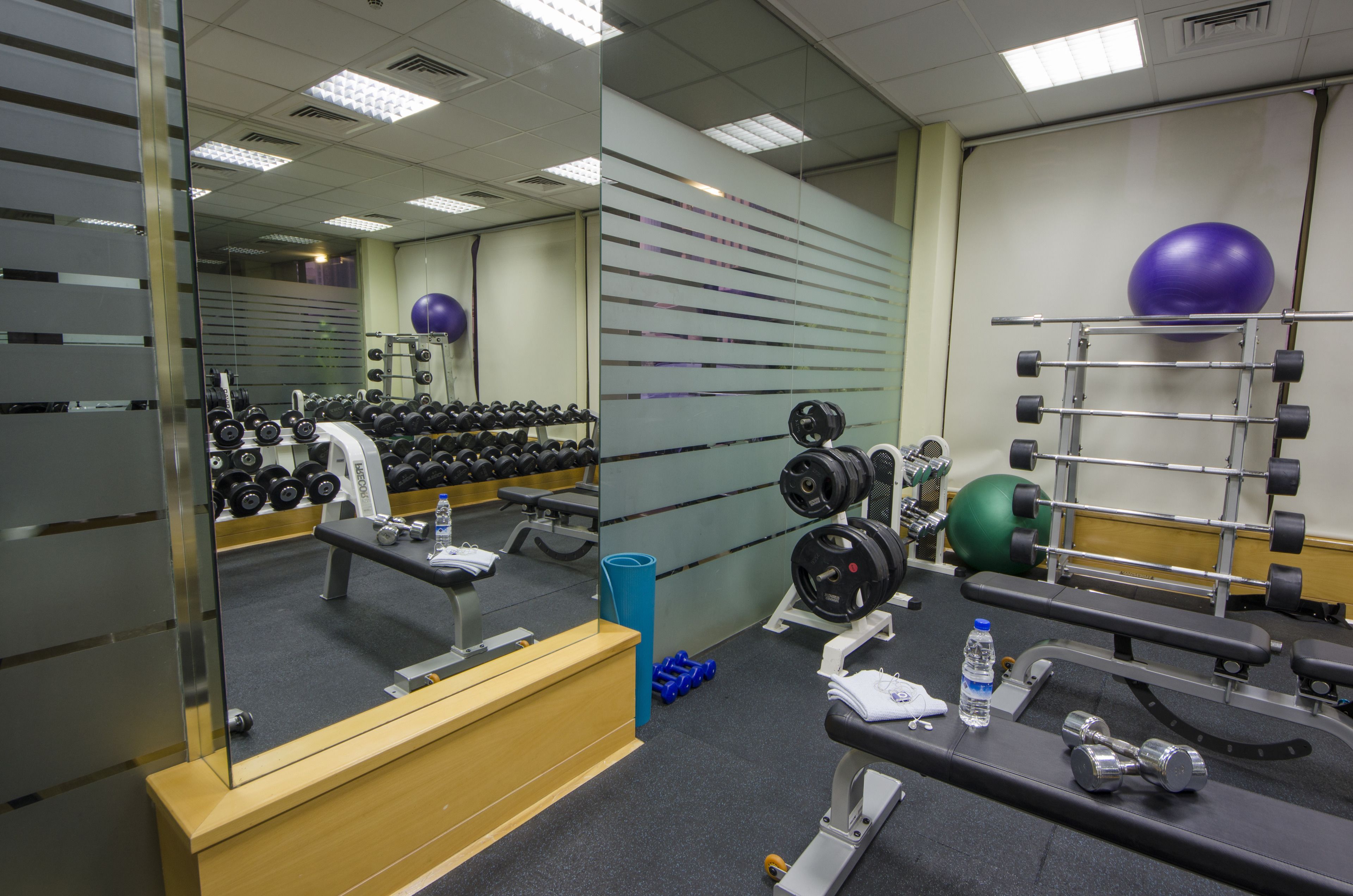 Uma academia com equipamentos de musculação, um banco e bolas de exercícios.