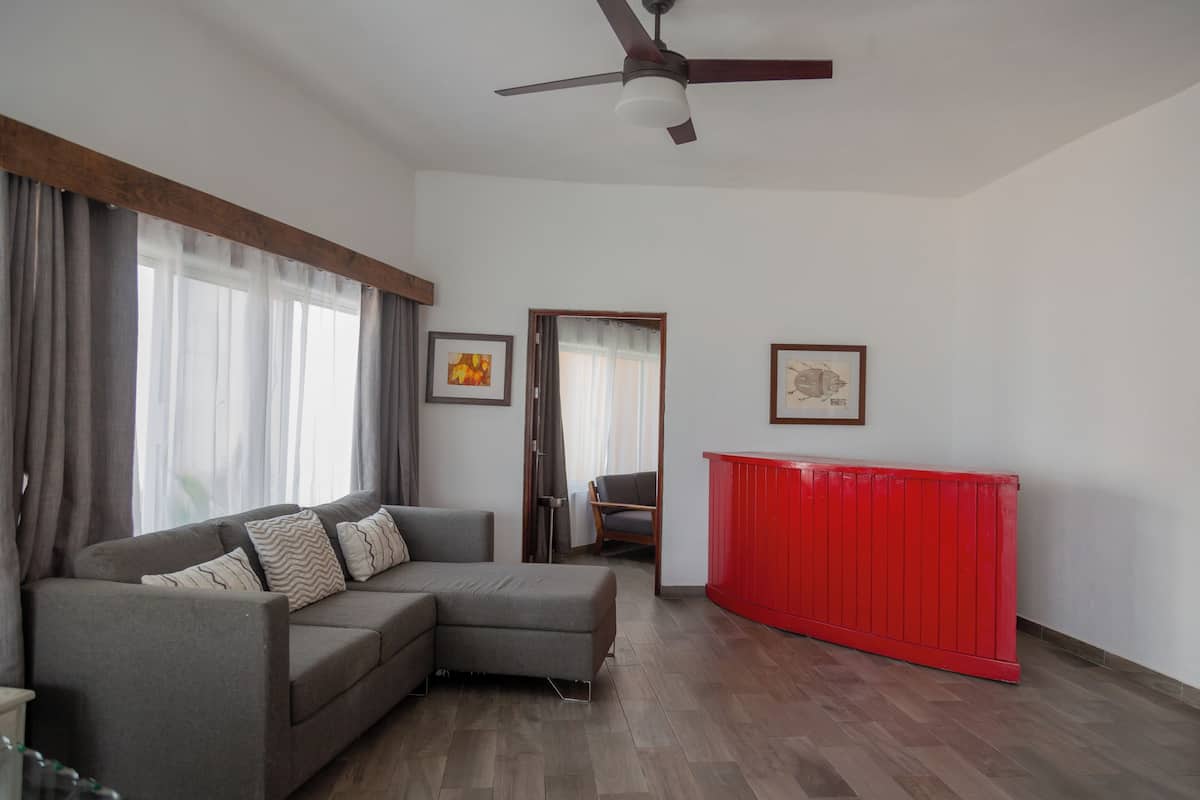 Uma sala de estar com sofá seccional, um radiador vermelho e um ventilador de teto.