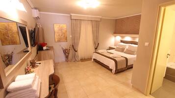 Quarto de hotel com cama, escrivaninha e cadeira, toucador com espelho e banheiro.