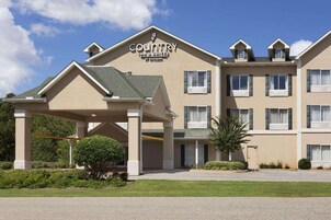 Edifício do Country Inn & Suites com entrada coberta, várias varandas e um jardim frontal ajardinado.