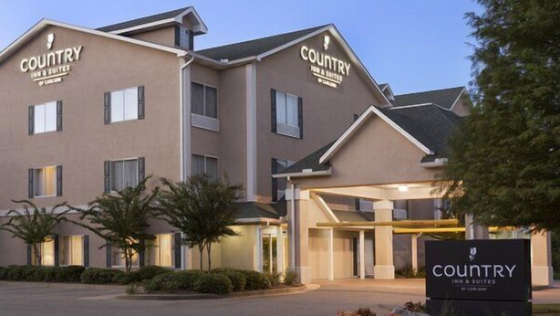 Um hotel Country Inn & Suites com design moderno, apresentando uma estrutura de dois andares e uma entrada coberta.