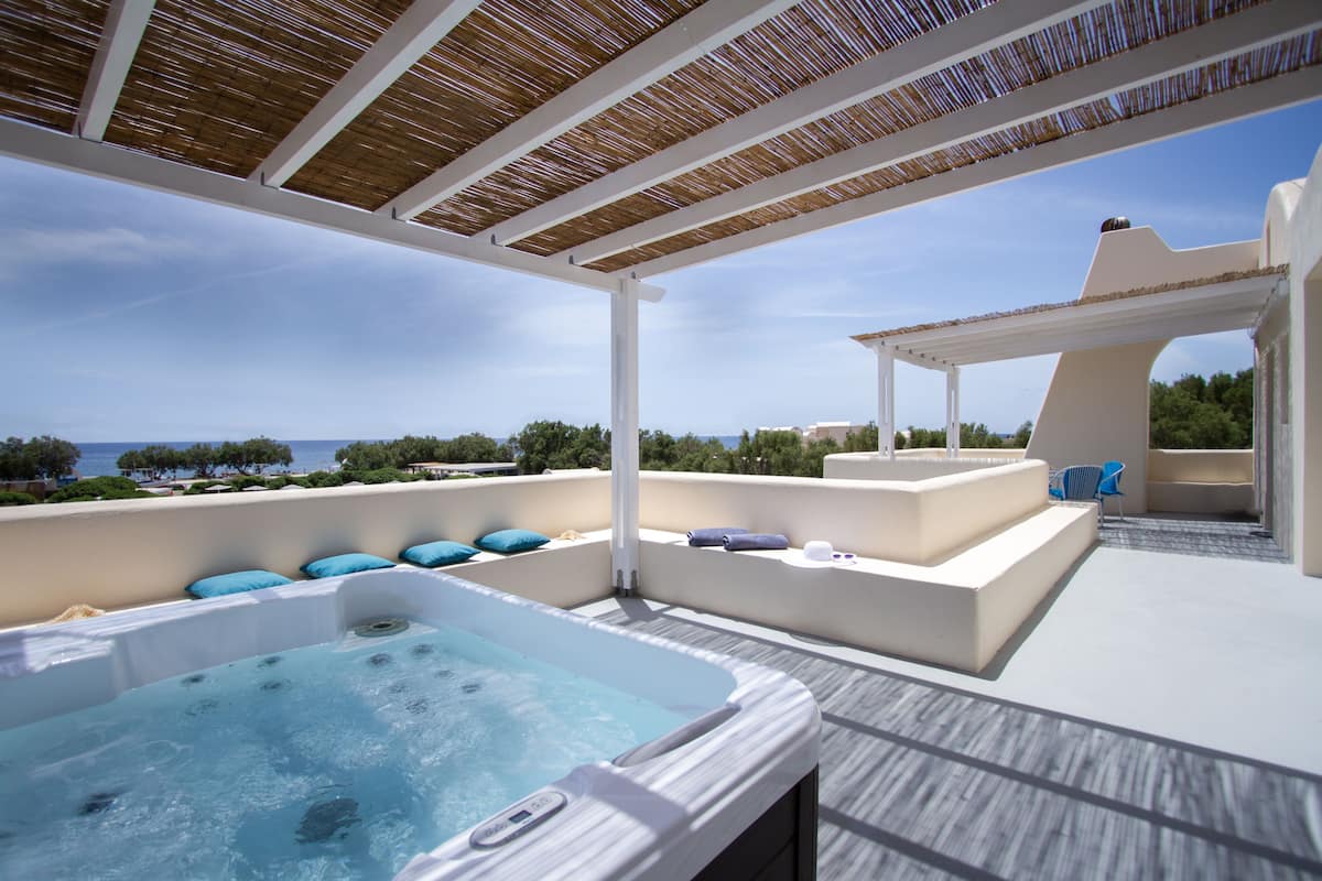 Terraço no telhado com banheira de hidromassagem, área de estar e vista para o mar.