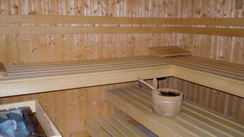 Uma sauna de madeira com bancos e um balde.