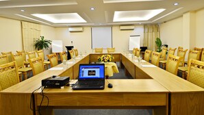 Uma sala de conferências com uma mesa comprida, cadeiras, um laptop e um projetor.