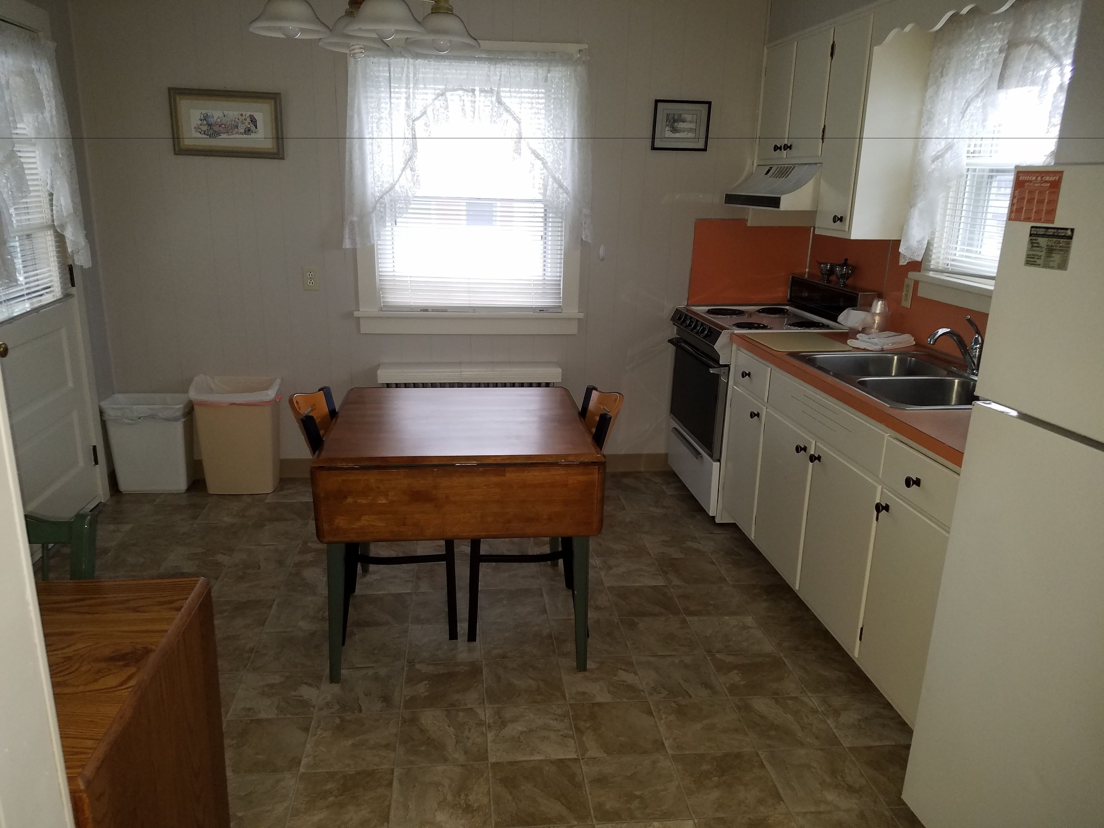 Cozinha compacta com mesa de jantar, fogão, pia e armários.