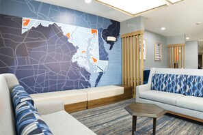 Um lobby moderno com um grande mapa na parede, áreas de estar e uma mesa de recepção.