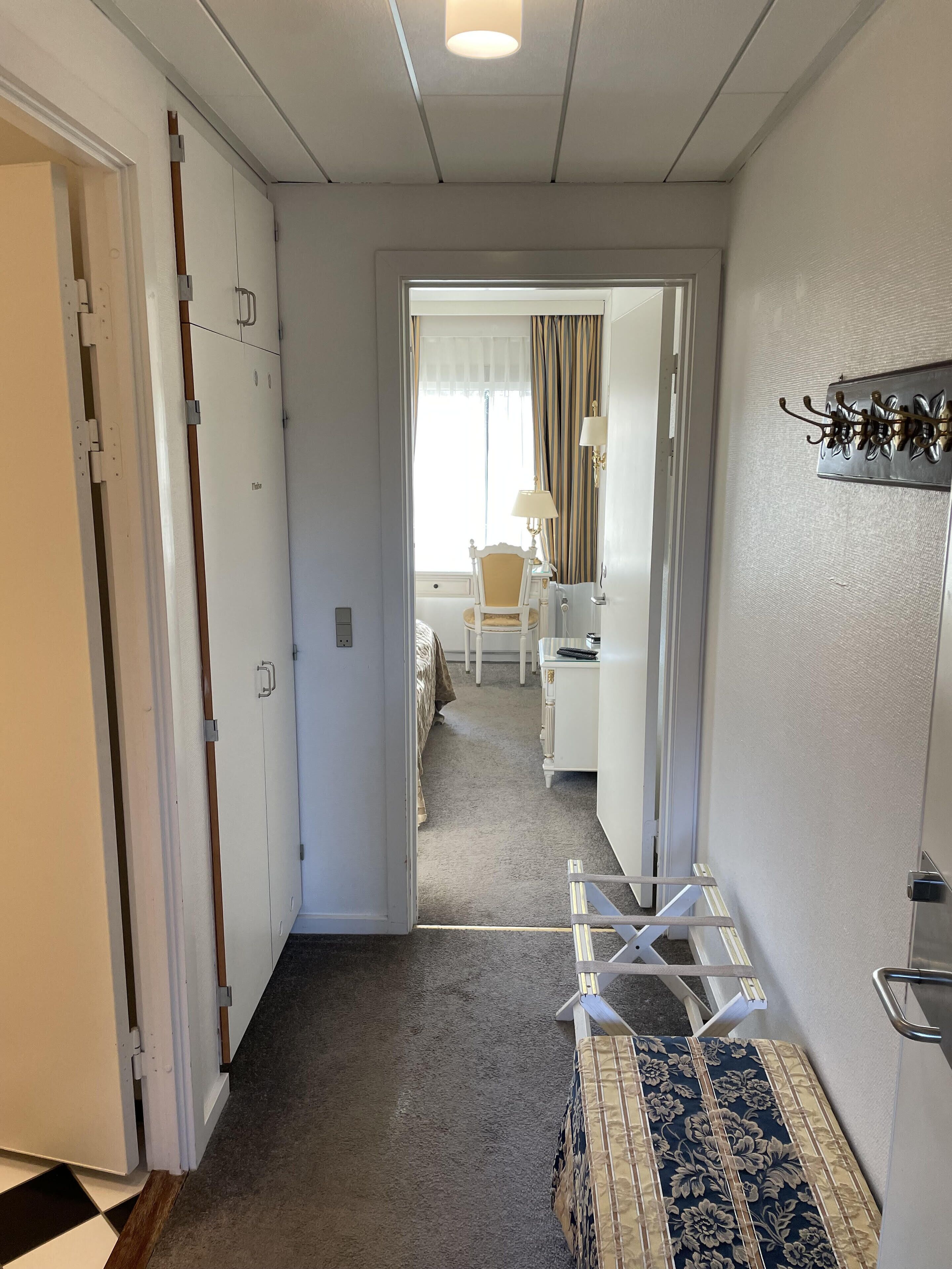 Corredor de hotel com uma cama, uma cadeira e uma mesa.