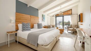 Quarto de hotel moderno com uma cama grande, uma escrivaninha, uma cadeira e vista para a cidade.