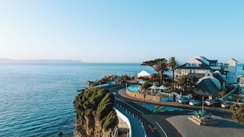 Uma estrada costeira com área de piscina, palmeiras e vista para o mar.