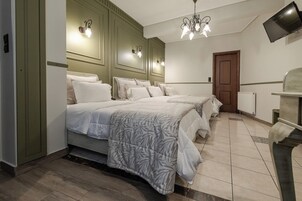 Quarto de hotel com uma cama grande, uma escrivaninha, uma cadeira, uma televisão e uma porta.