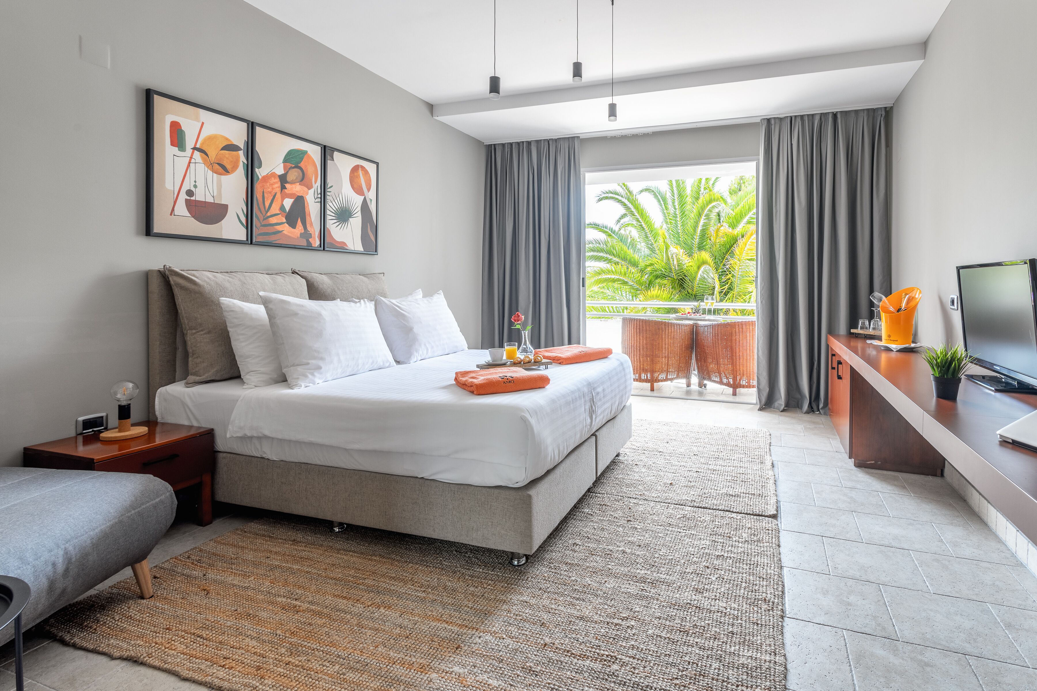 Quarto moderno com uma cama grande, uma escrivaninha e varanda com vista para o verde.