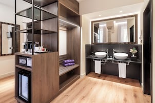 Uma casa de banho moderna com uma pia dupla, um espelho grande e um móvel embutido com prateleiras e frigorífico.