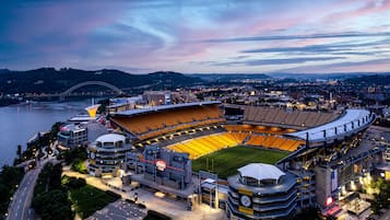 Um estádio com uma extensa área de assentos, um campo e uma ponte ao fundo.