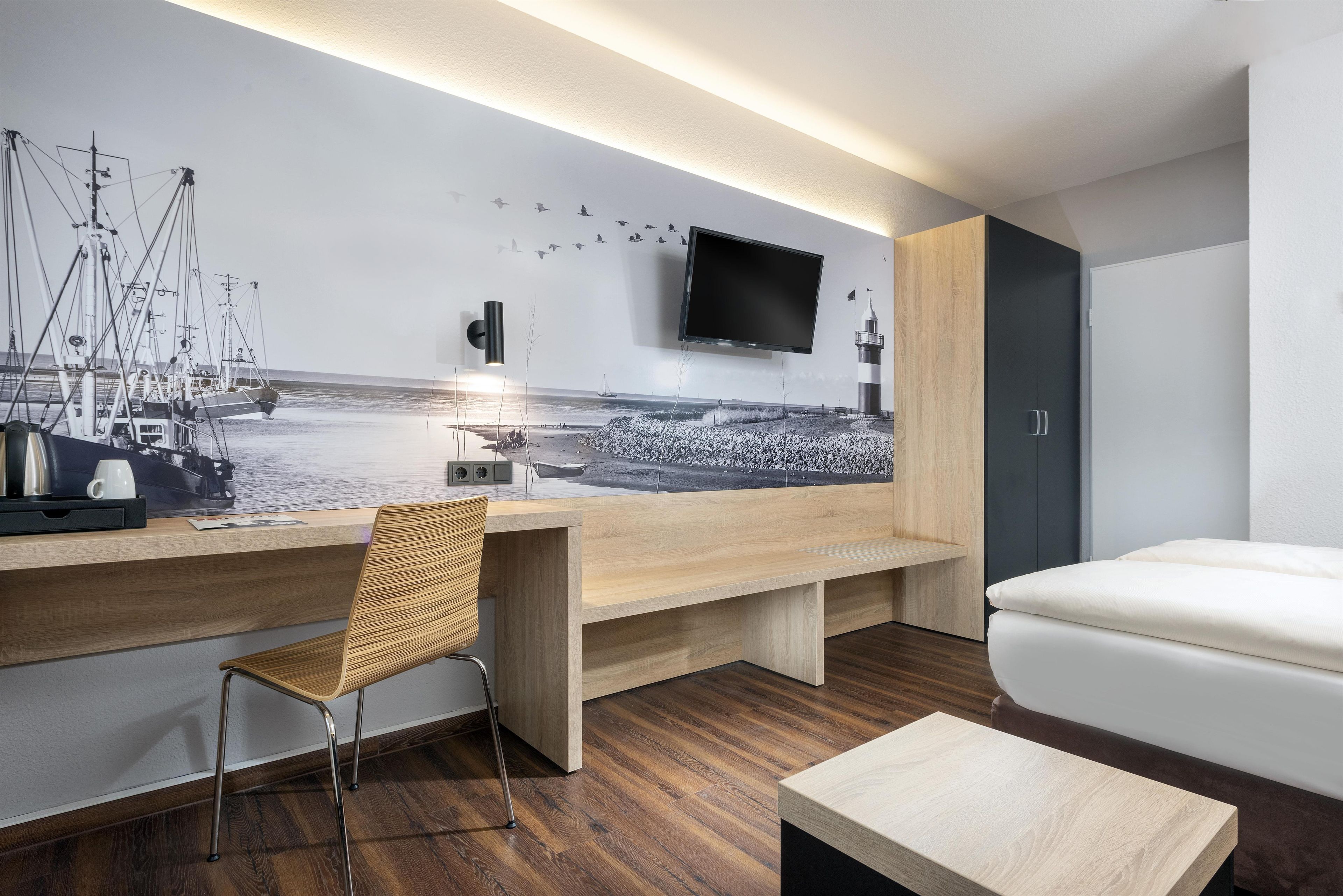 Quarto moderno com escrivaninha de madeira, uma cadeira, televisão de tela plana e uma cama.