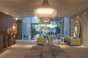 Um hall moderno com um lustre grande, móveis de vime e um relógio de parede imponente.