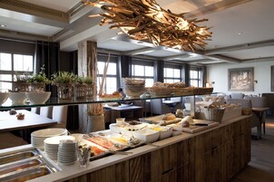 Disposição de buffet com diversos tipos de comida, um expositor de vidro e um pendente de madeira exclusivo.