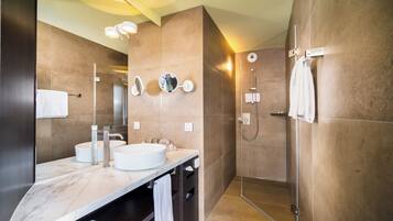 Casa de banho moderna com um espelho grande, duas pias, um chuveiro e um porta-toalhas.