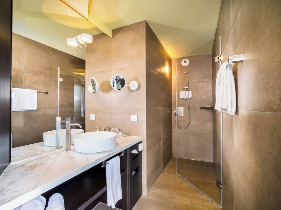 Casa de banho moderna com um espelho grande, duas pias, um chuveiro e um porta-toalhas.