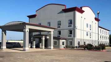 Um hotel com vários andares, área de estacionamento coberta e design arquitetônico moderno.