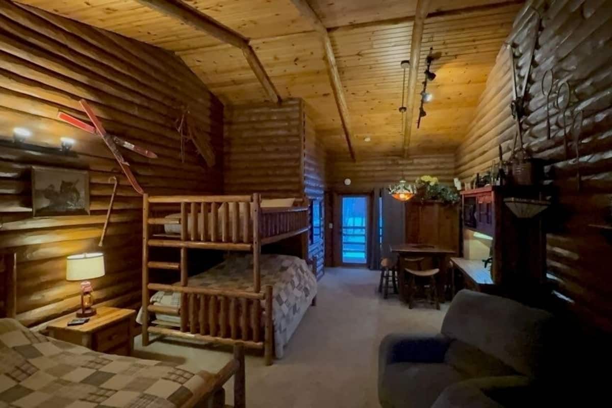 Interior acolhedor de uma cabana com beliche, um pequeno espaço de jantar e lareira.