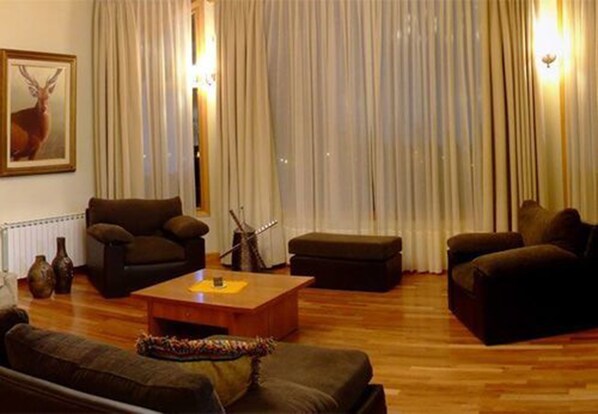 Uma sala de estar com sofá, poltronas, mesa de centro e uma guitarra.