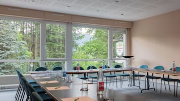 Uma sala de conferências com grandes janelas, uma mesa comprida e cadeiras.