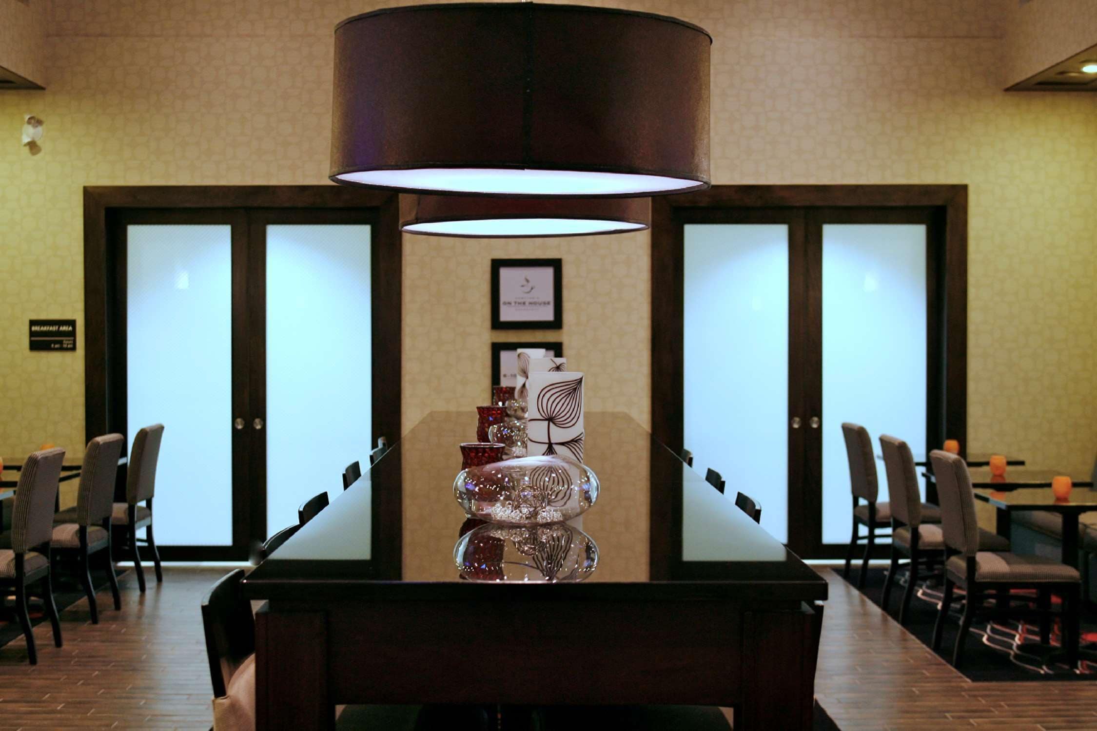 Uma sala de conferências com uma mesa comprida, cadeiras e um abajur grande.