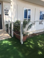 Um edifício com fachada branca, número 10, e uma pequena varanda com deck de madeira.