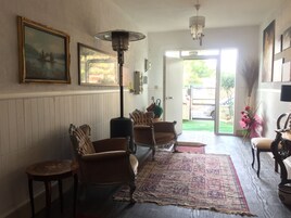 Um quarto com um tapete grande, algumas cadeiras, uma mesa e um abajur.