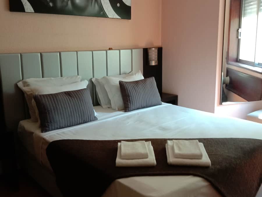 Quarto de hotel com uma cama grande, cabeceira com design circular e uma obra de arte pendurada na parede.