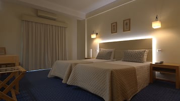 Quarto de hotel com duas camas, uma escrivaninha e uma cadeira.