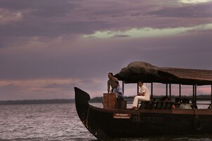 Um barco com cobertura no deque e passageiros.