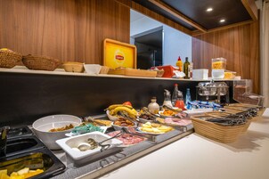 Buffet com diversos alimentos e utensílios.