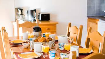 Uma mesa de café da manhã posta com pratos, tigelas, xícaras e uma cafeteira.