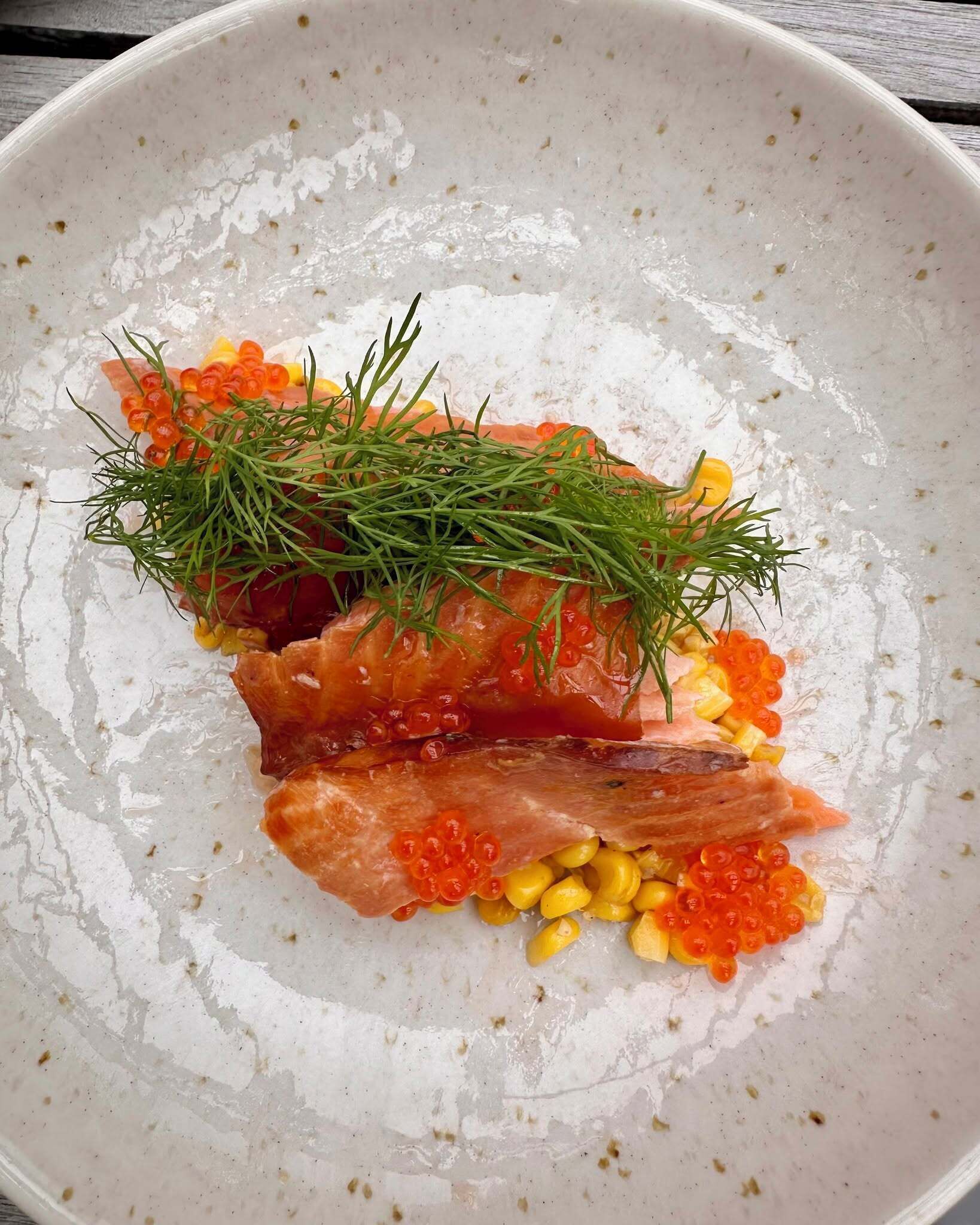 Um prato com salmão, caviar, grãos de milho e endro.
