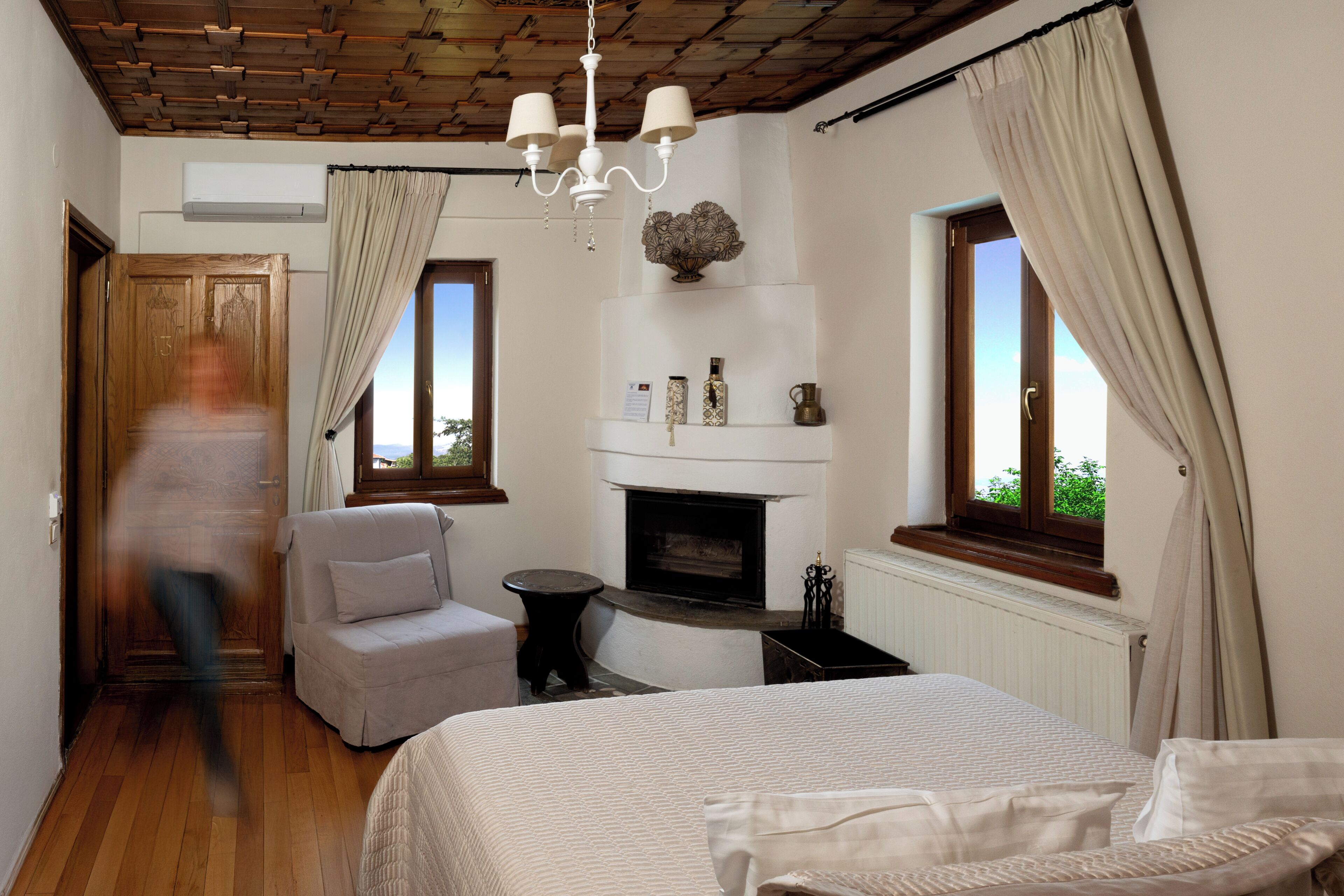 Quarto com cama, cadeira, lareira e janela com cortinas.